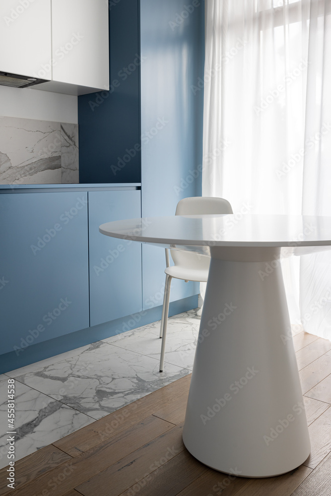 Round white table in a blue kitchen with marble floor Stock Photo ...