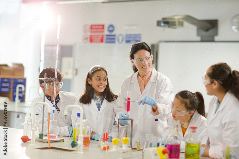 Female teacher and students conducting scientific experiment, watching ...