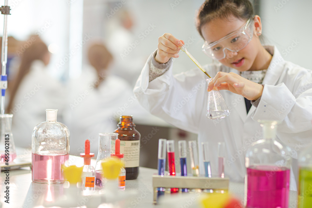 Girl student examining pink liquid, conducting scientific experiment in ...