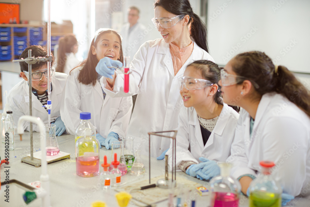 Female teacher and students conducting scientific experiment, watching ...