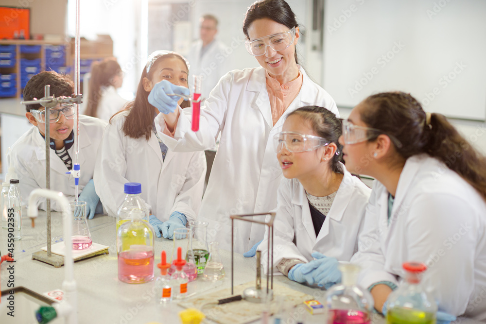 Female teacher and students conducting scientific experiment, watching ...