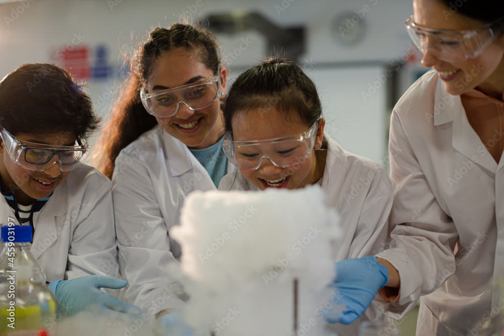 Female teacher and students watching scientific experiment chemical ...