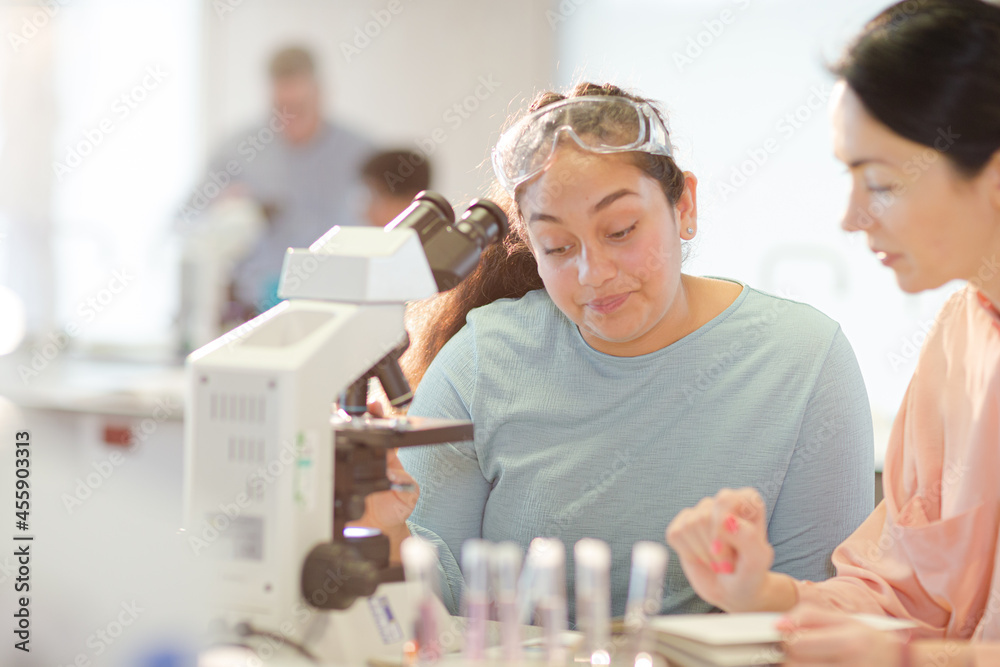 Female teacher and girl student conducting scientific experiment at ...