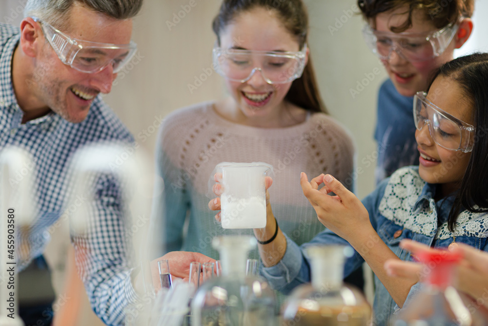 Male teacher and students watching chemical reaction, conducting ...