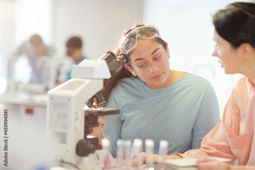 Female teacher and girl student conducting scientific experiment at ...