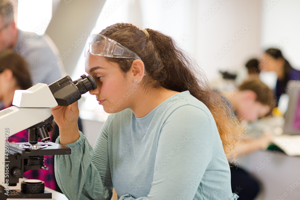 Girl student using microscope in classroom Stock Photo | Adobe Stock