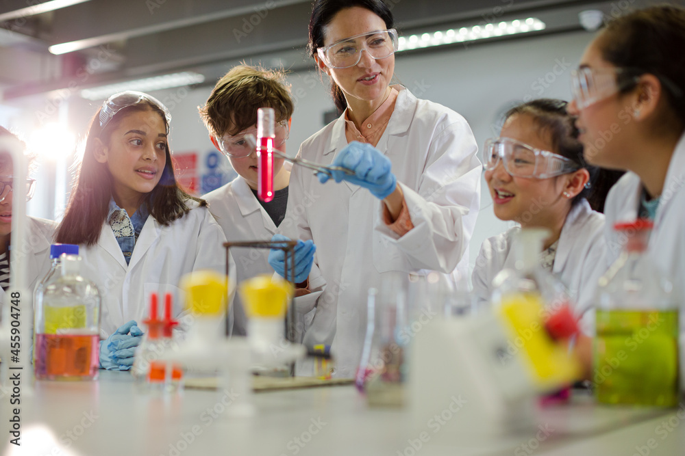 Female teacher and students conducting scientific experiment, watching ...