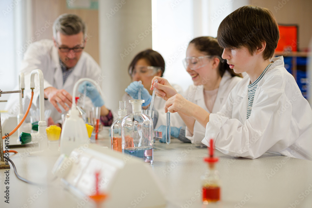 Male teacher and students conducting scientific experiment in ...