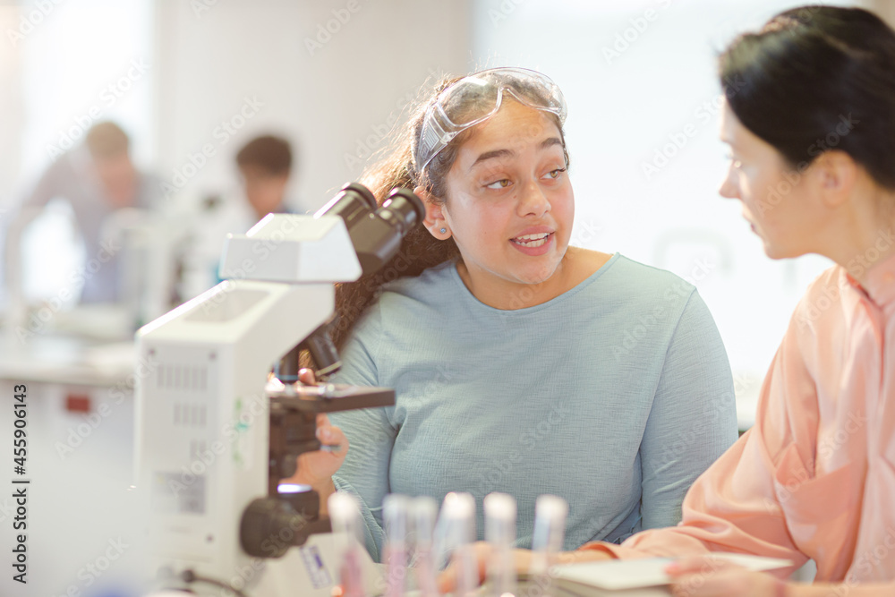 Female teacher and girl student conducting scientific experiment at ...