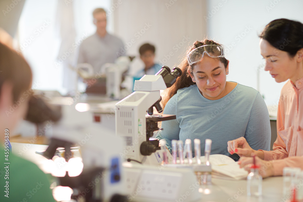 Female teacher and girl student conducting scientific experiment at ...