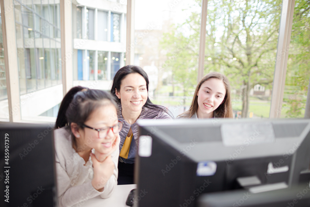 Female teacher and students using computer in library Stock Photo ...