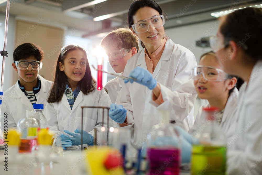 Female teacher and students conducting scientific experiment, watching ...
