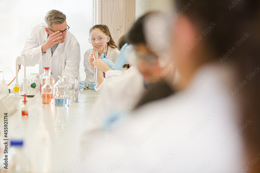 Male teacher and students conducting scientific experiment in ...