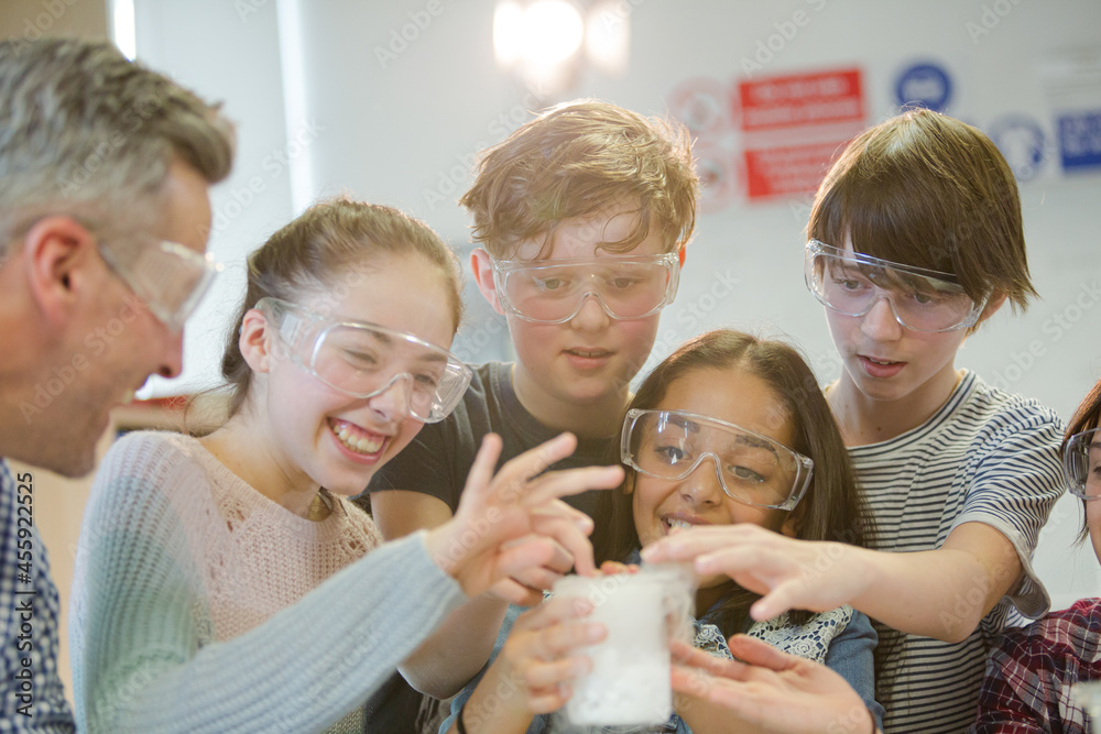 Curious, smiling students watching chemical reaction, conducting ...