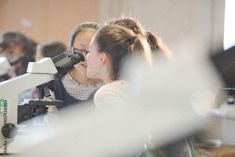 Girl students using microscope, conducting scientific experiment in ...