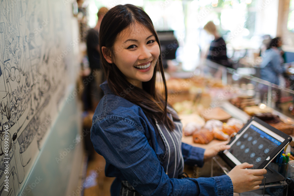 Smiling cashier using touch screen cash register in cafe Stock Photo ...
