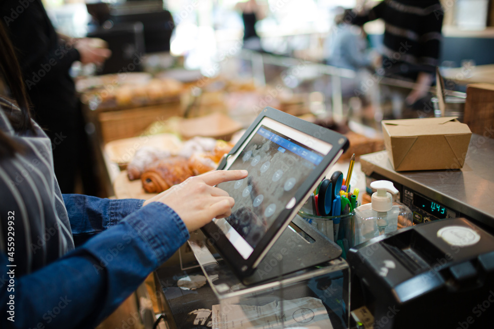 Smiling cashier using touch screen cash register in cafe Stock Photo ...