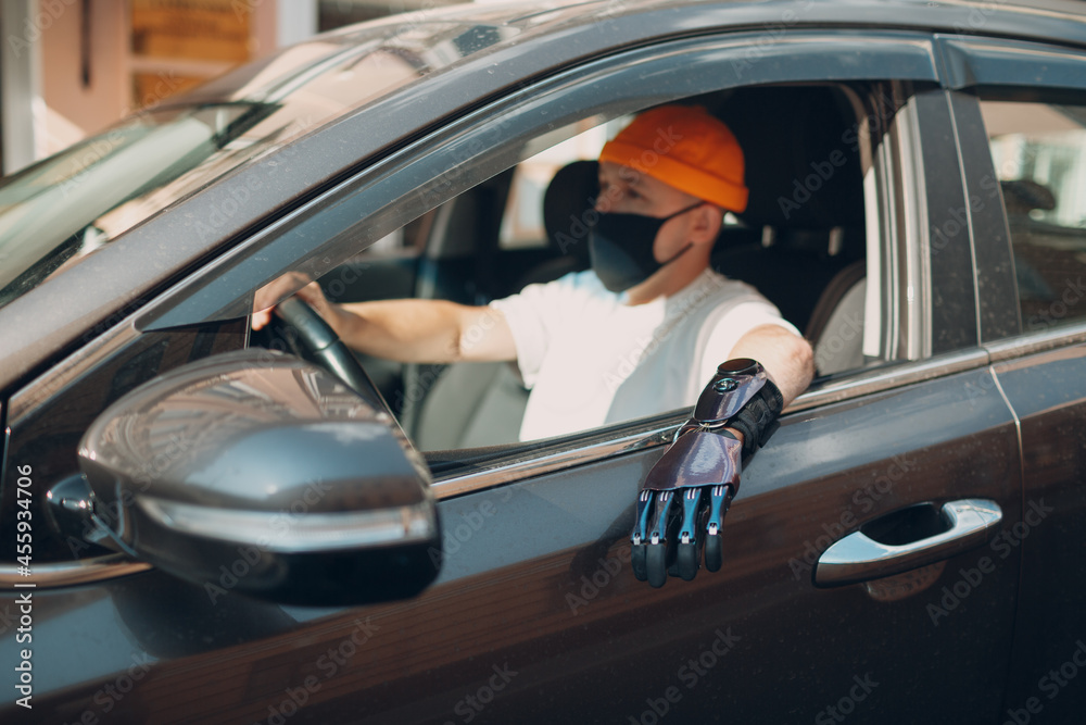 Young disabled man driver with artificial prosthetic hand driving ...
