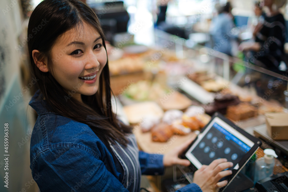 Smiling cashier using touch screen cash register in cafe Stock Photo ...