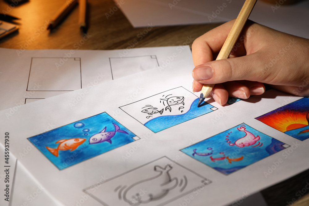 Woman drawing cartoon sketch in storyboard at workplace, closeup. Pre ...