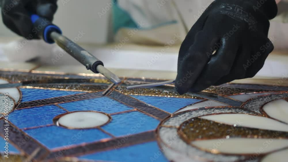 Close-up Soldering of stained glass seams. Gloved artist's hands with a ...