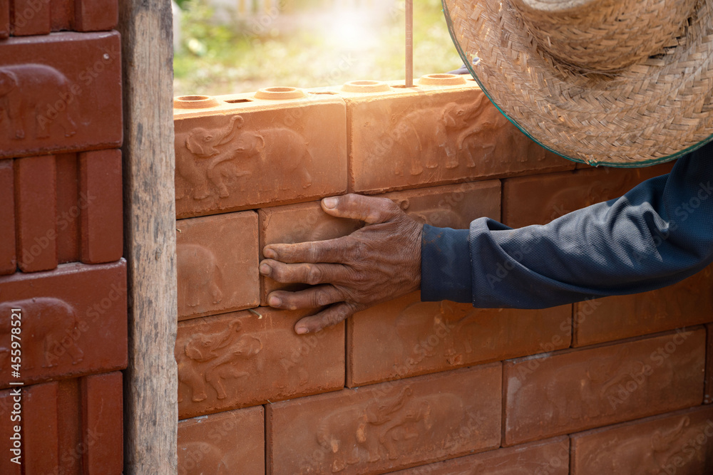 Builder carefully puts red brick on the masonry. Quick work bricklayer ...