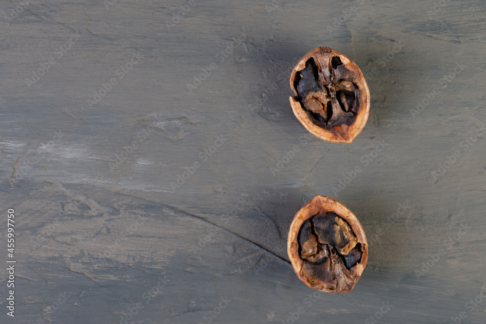 half of a split rotten walnut on a brown concrete or slate background ...