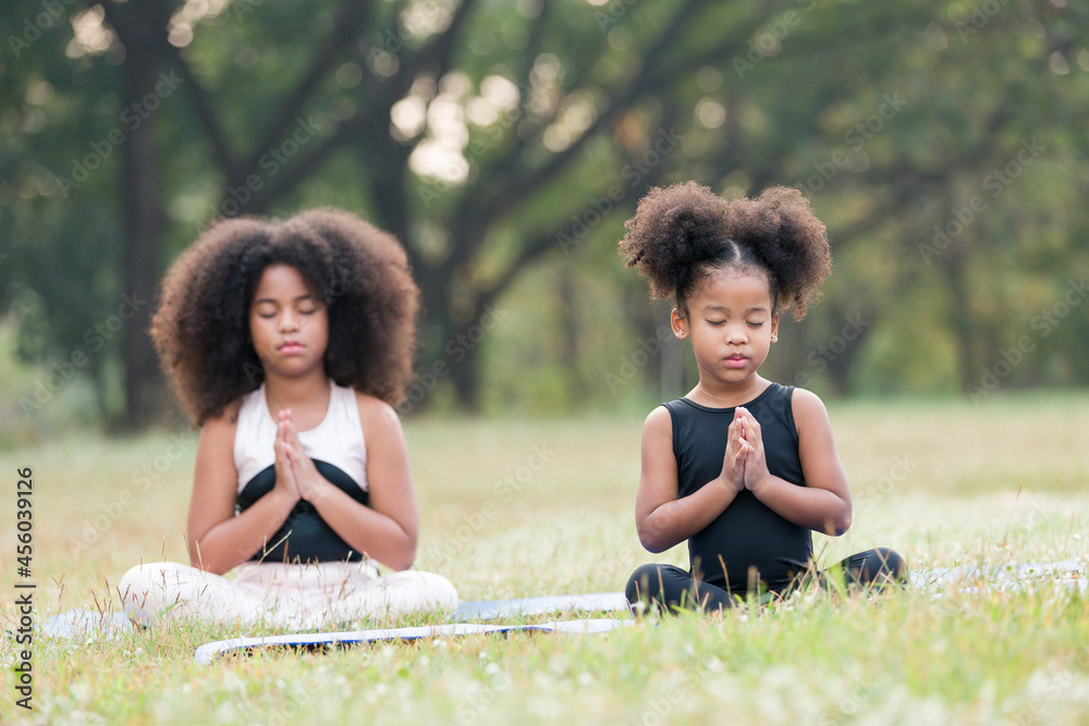 Two African American little girl doing meditate yoga asana on roll mat ...
