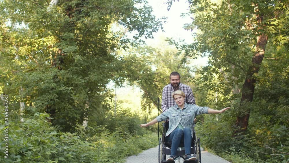 Man rolls emotional disabled woman in wheelchair, who spread her arms ...