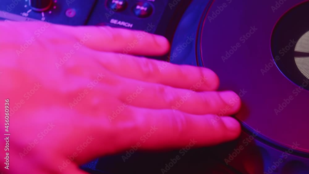 Male DJ's hand presses play button and rotates round platform on ...