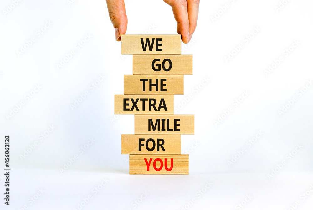 Go the extra mile symbol. Wooden blocks with words 'We go the extra ...