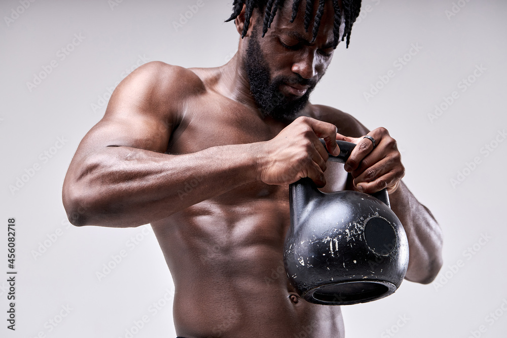 Portrait of strong young african man working out with kettle bell ...