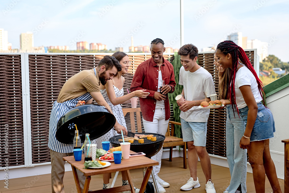 Young positive friends having barbecue party on the evening on house ...