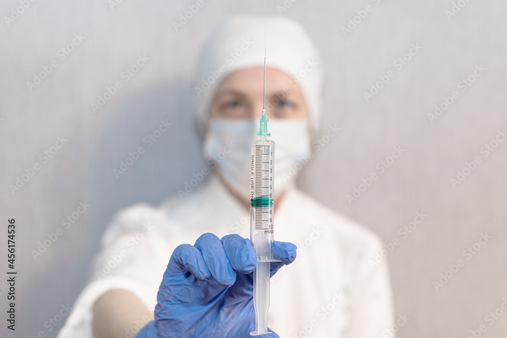 A doctor wearing a Protection suit holding syringe with vaccine against ...
