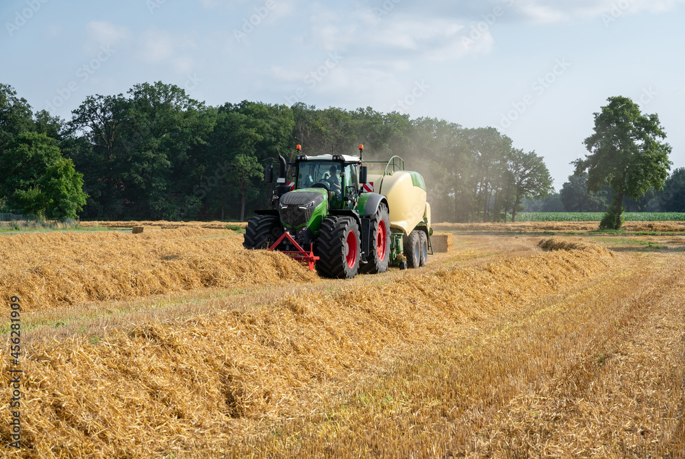 Foto Stock Strohernte - Traktor mit moderner Hochdruckpresse beim ... Foto Stock Strohernte - Traktor mit moderner Hochdruckpresse beim ...