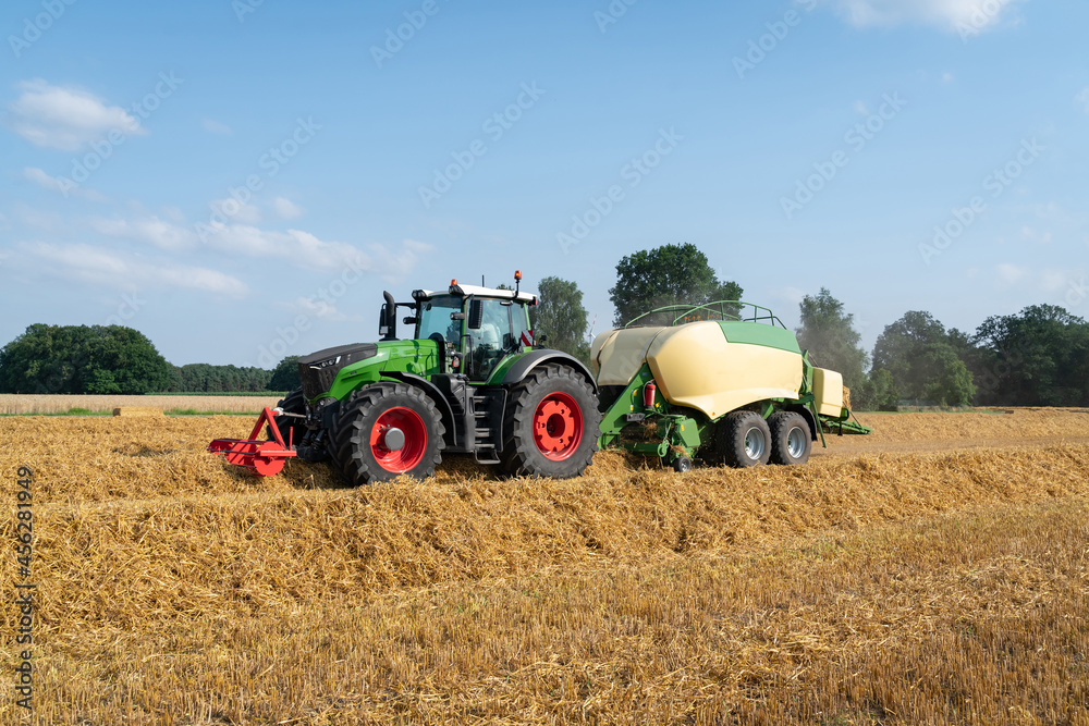 Strohernte - Traktor mit moderner Hochdruckpresse beim Pressen von ... Strohernte - Traktor mit moderner Hochdruckpresse beim Pressen von ...