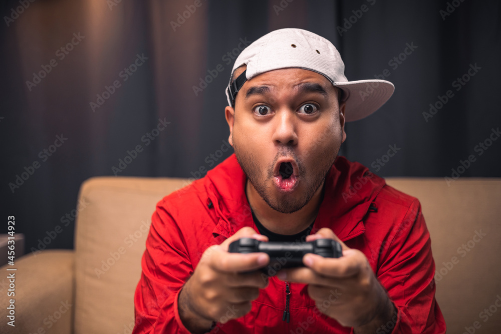 Excited and shocked face of Asian gamer holding headset playing video ...