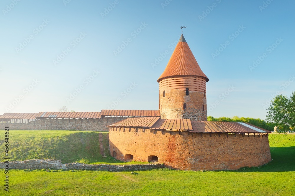 Red brick medieval castle tower and wall against clear blue sky. Kaunas ...