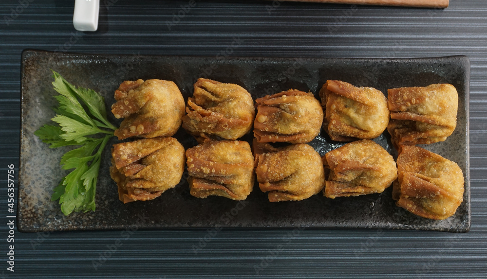 handmade deep fried and boiled pork meat dumpling wanton soup on dark ...