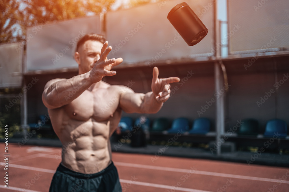 muscular athlete man throw up black container with protein whey powder ...