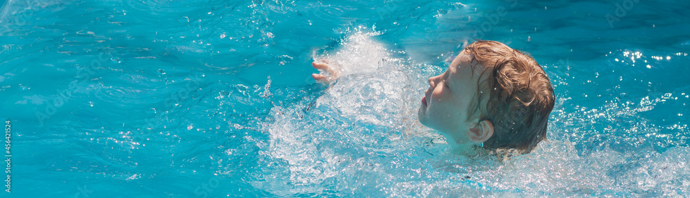 A Caucasian boy of 7 years old learns to swim in the pool in the summer ...