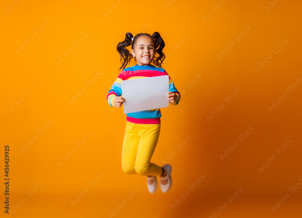 Cute little girl with a white sheet of paper. yellow background little ...