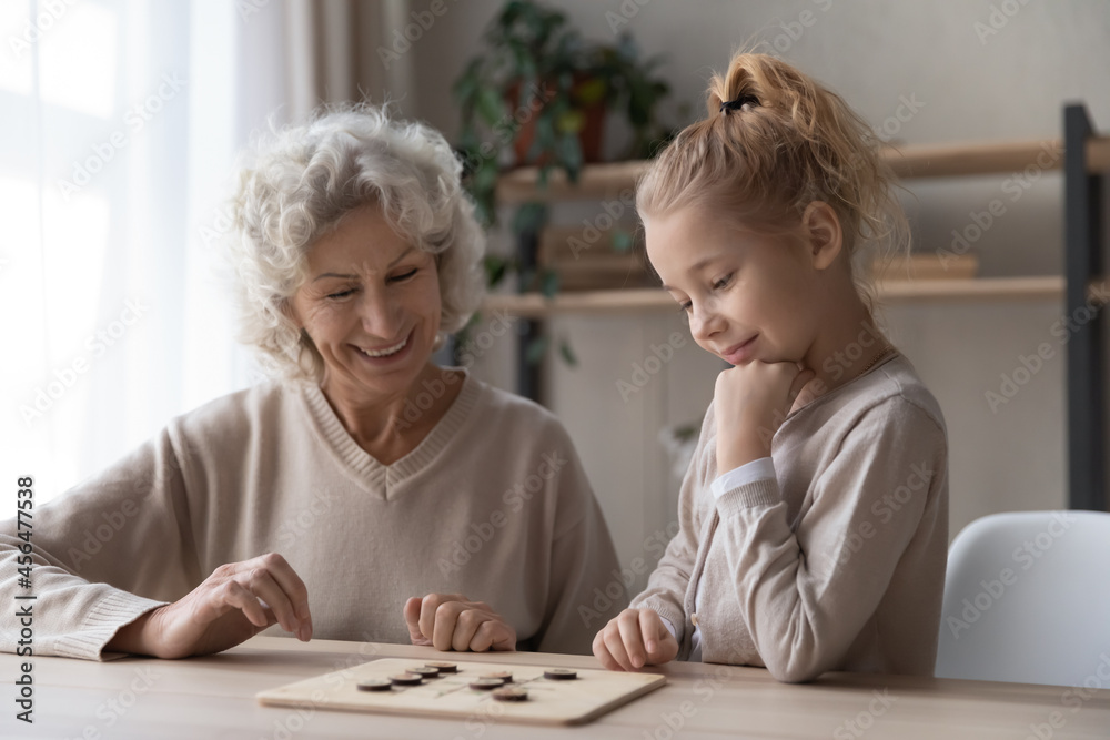 Caring middle aged old grandmother playing draughts with adorable ...