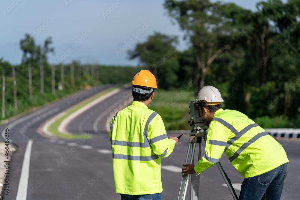 Teamwork of surveyor engineers with equipment on road construction site ...