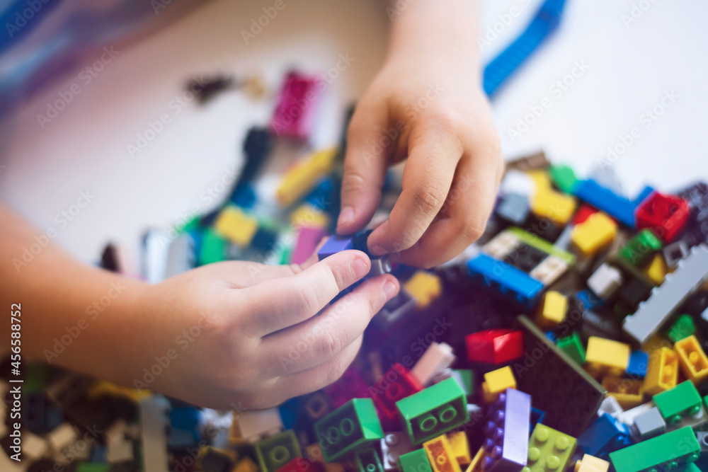 Hands of a child constructing Lego against the background of a heap of ...