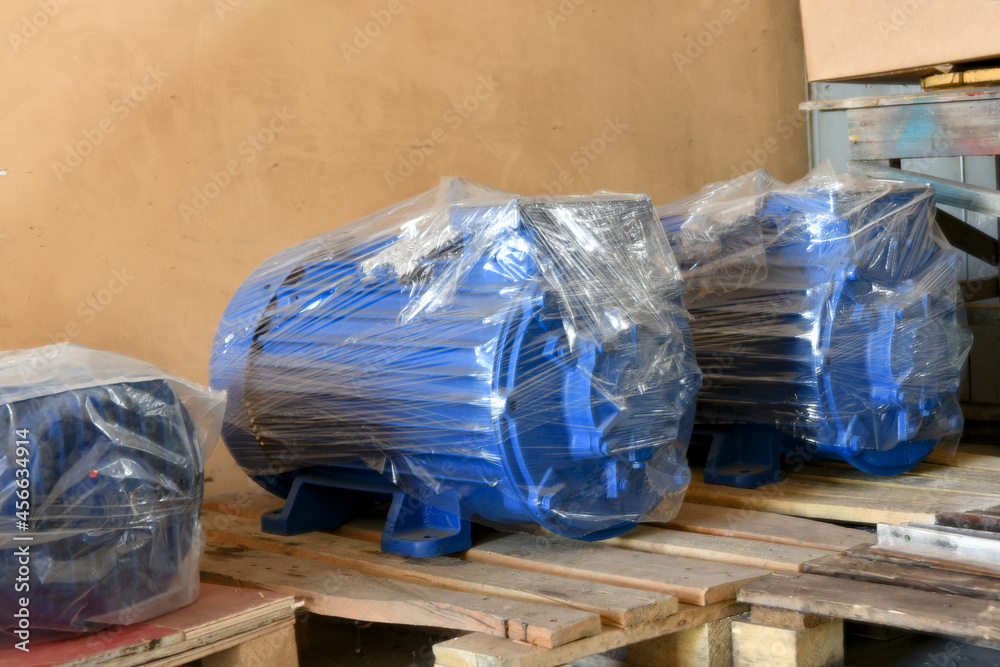 New electric motors are wrapped with packaging in the warehouse. Stock ...