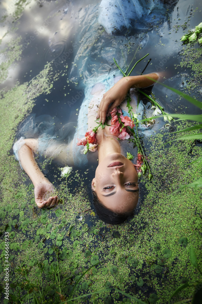 Art beautiful romantic woman lies in swamp in blue long dress with ...
