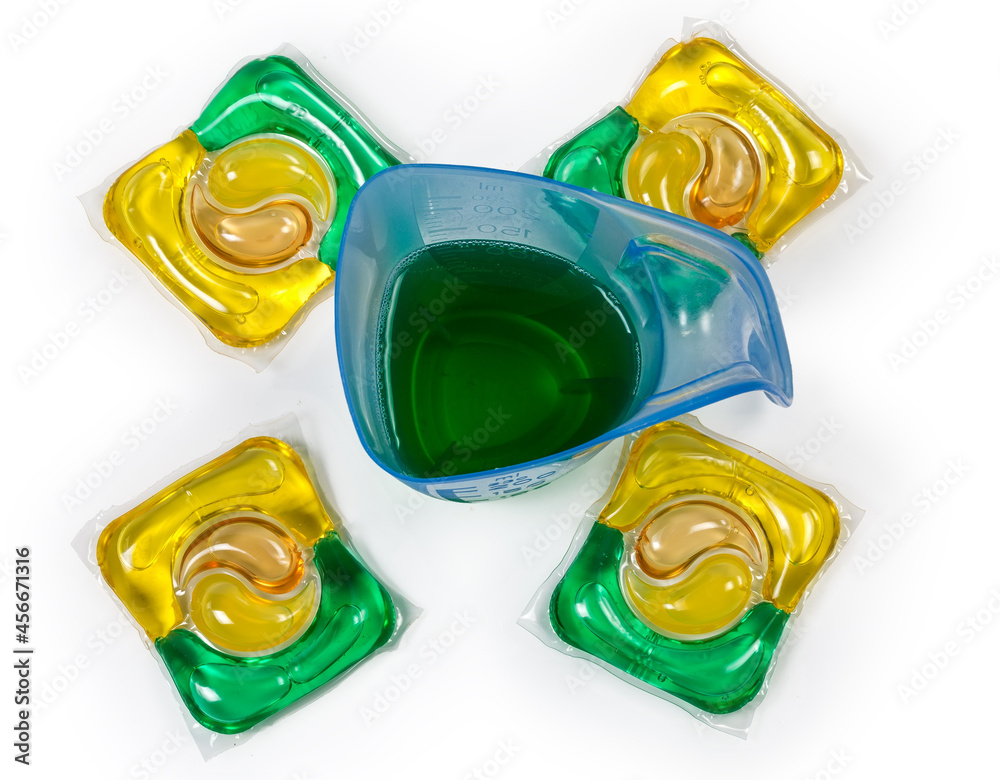 Measuring cup with liquid laundry detergent among the laundry capsules ...