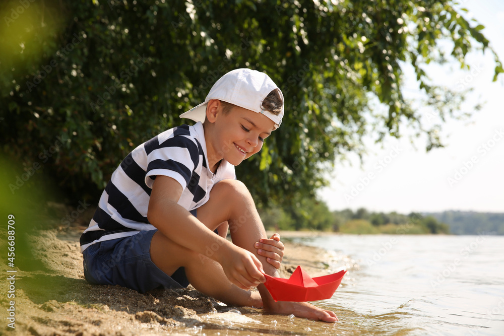 Cute little boy playing with paper boat near river Stock Photo | Adobe ...
