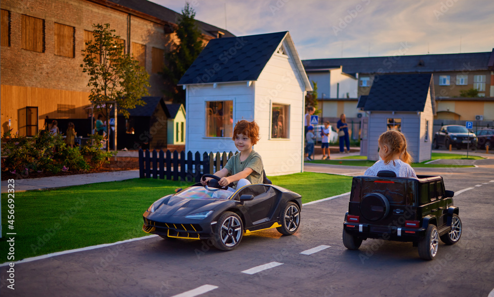 happy kids are driving the electric toy cars, moving around the toy ...